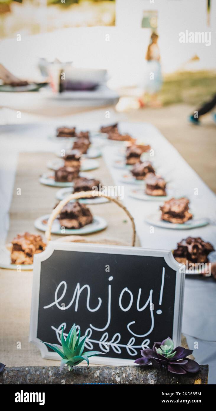 A vertical of a wedding reception sign for guests on a table with cake ...