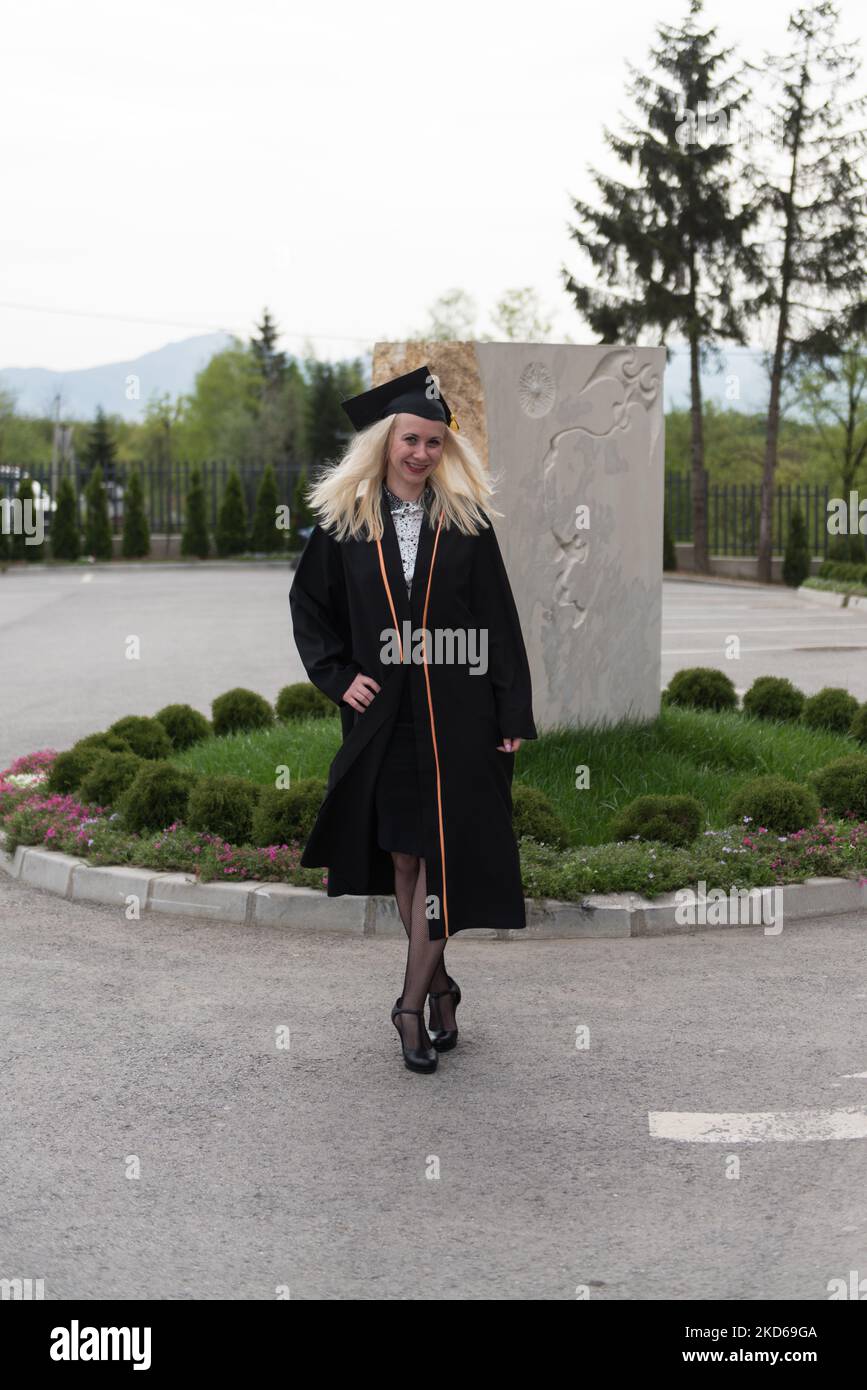 Young Happy Woman University Graduates in Graduation Gown and Cap Holds ...