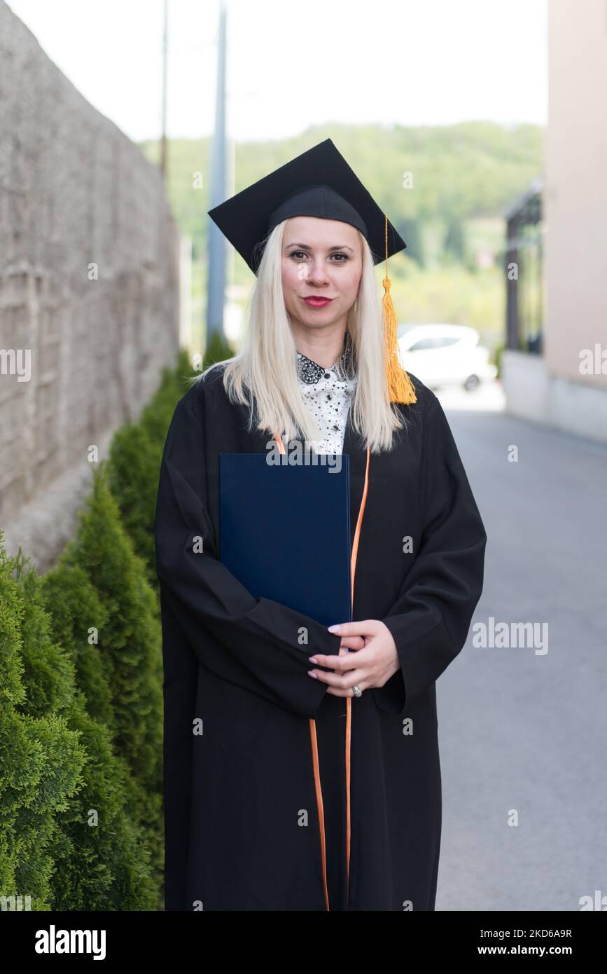 Young Happy Woman University Graduates in Graduation Gown and Cap Holds ...