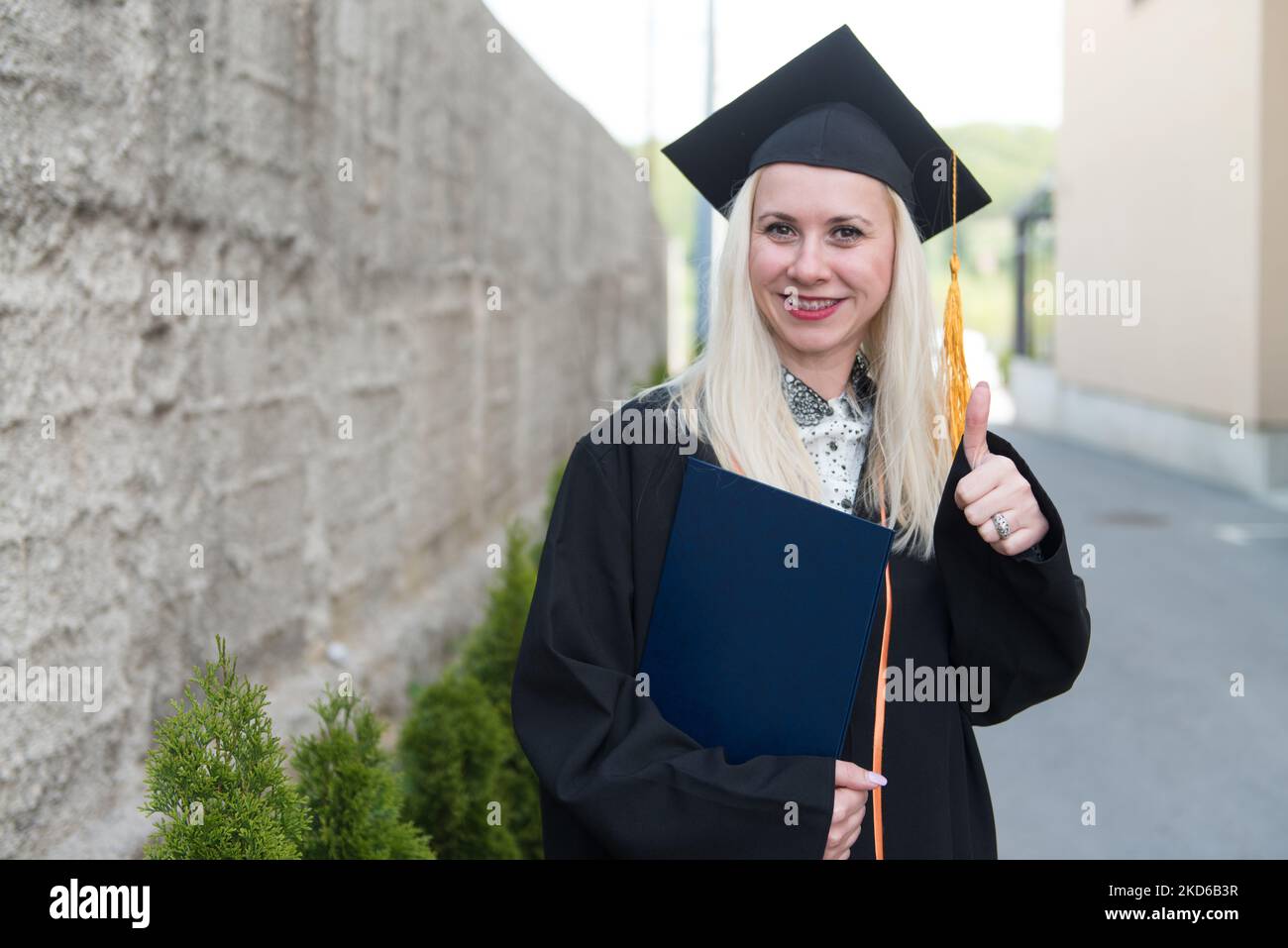 Young Happy Woman University Graduates in Graduation Gown and Cap Holds ...