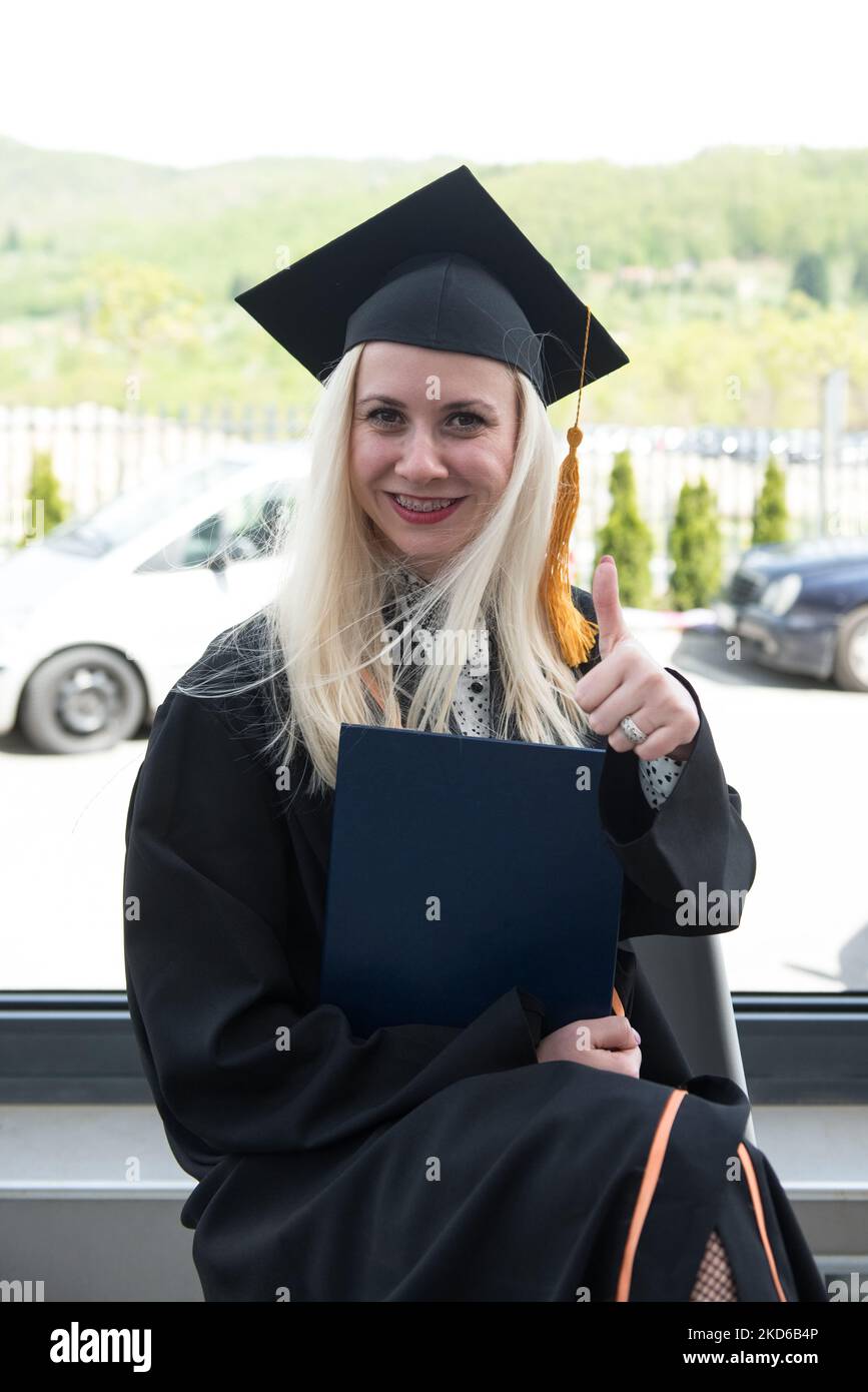 Young Happy Woman University Graduates in Graduation Gown and Cap Holds ...