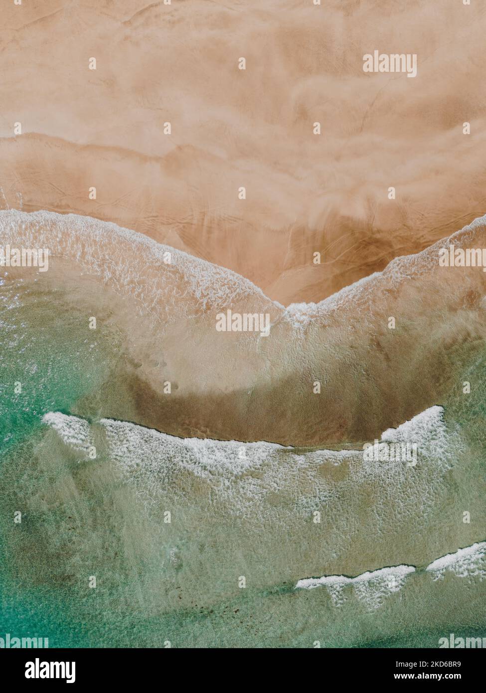 A vertical aerial view of sea waves coming onto a sandy shore Stock ...
