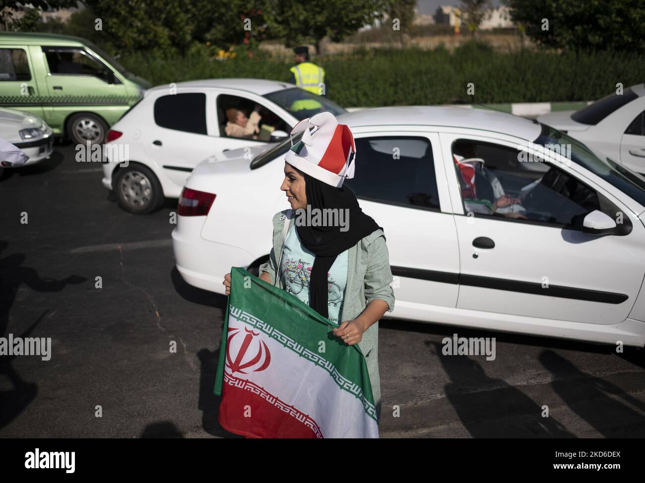 An Iranian soccer female fan wearing a hat as she holds an Iran flag ...