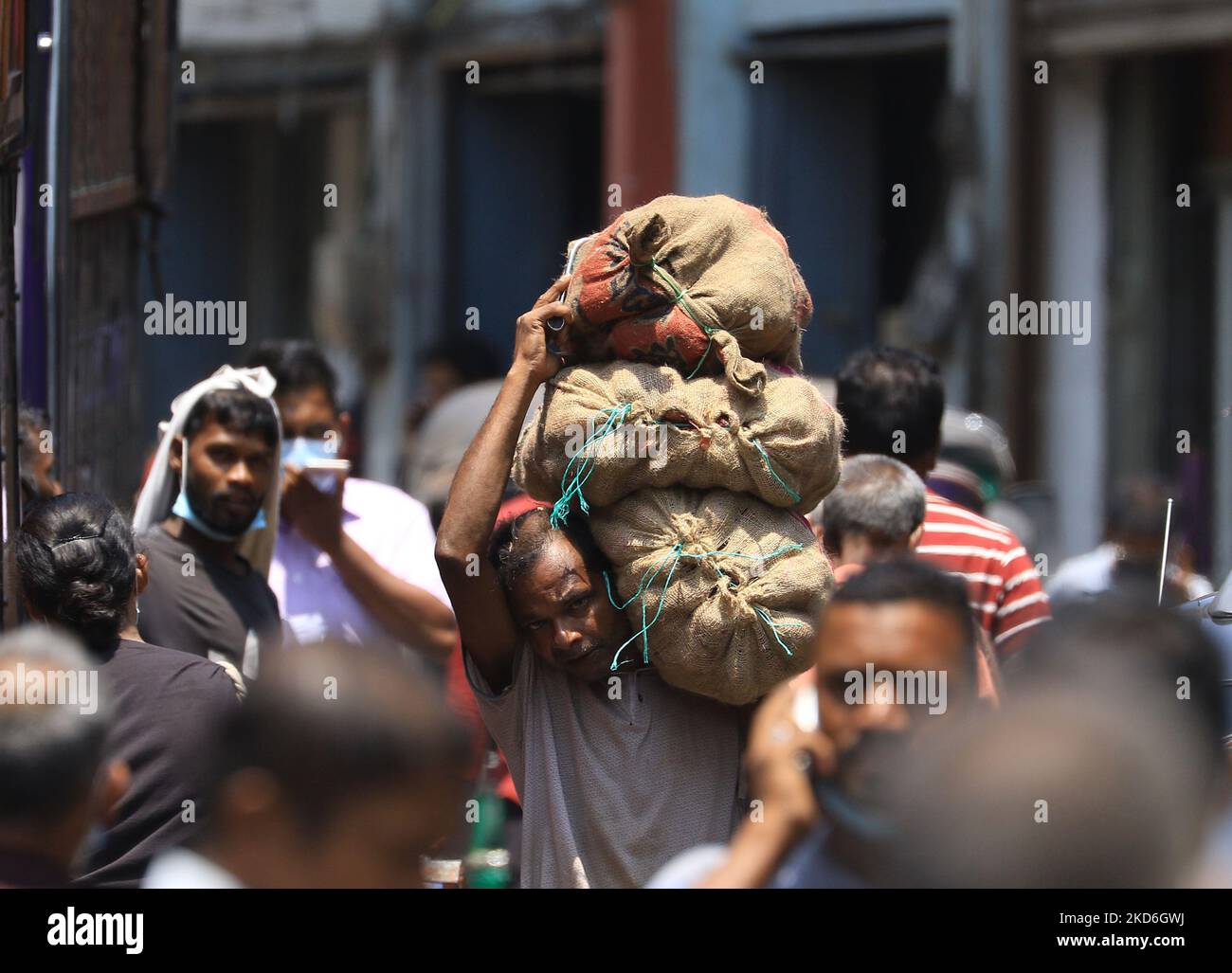 A Sri Lankan daily wage worker carries sacks of vegetables on his ...