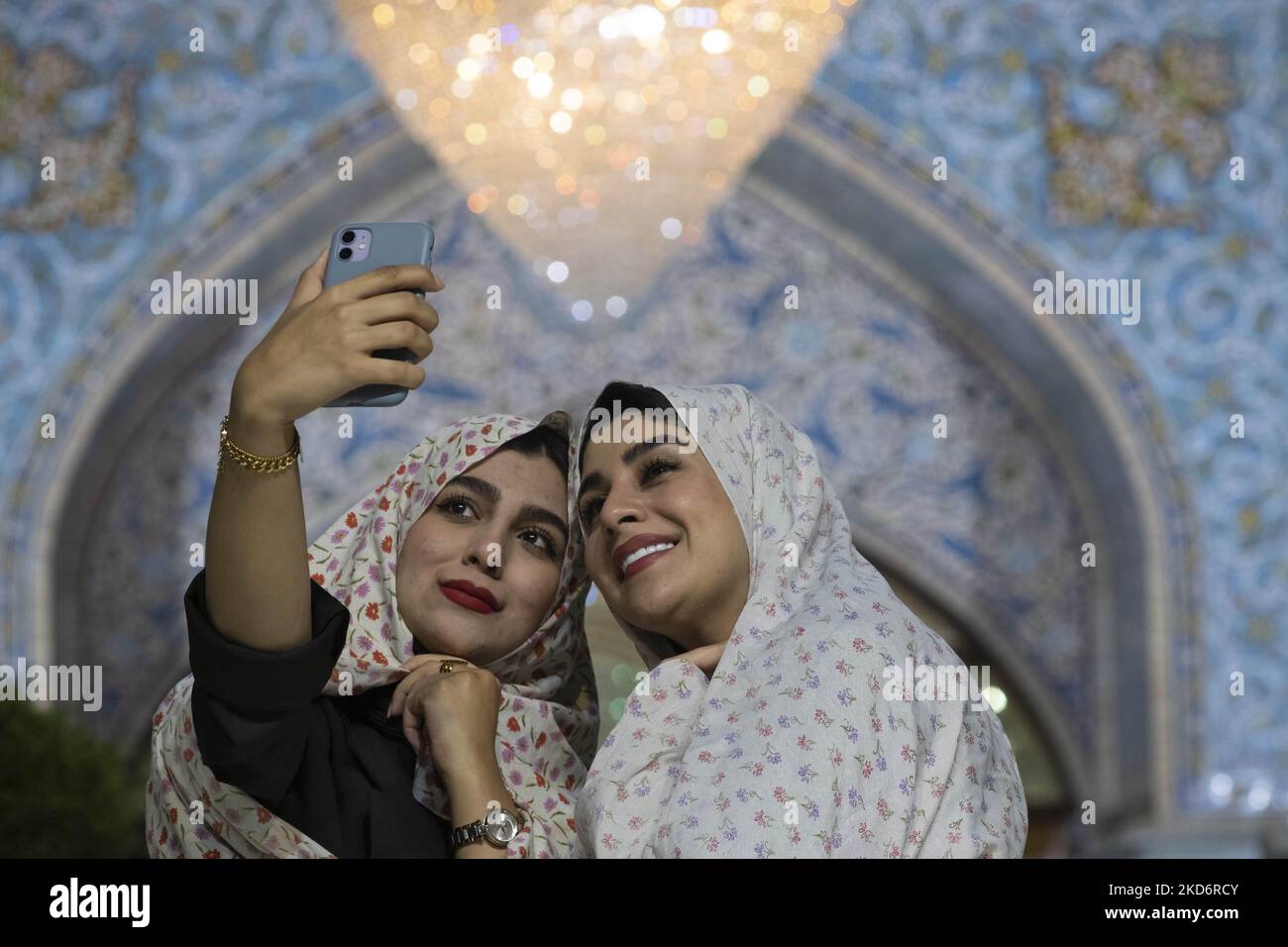 Two veiled women in white chadors (Islamic dressing code) take a selfie ...