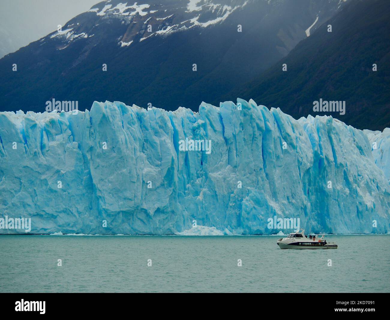 The Perito Moreno glacier with dark blue mountains behind and a side ...