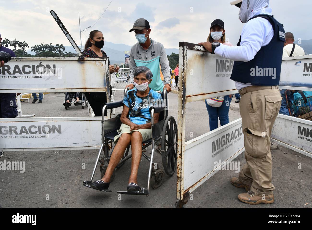 A person in a wheelchair is assisted while passing through the ...