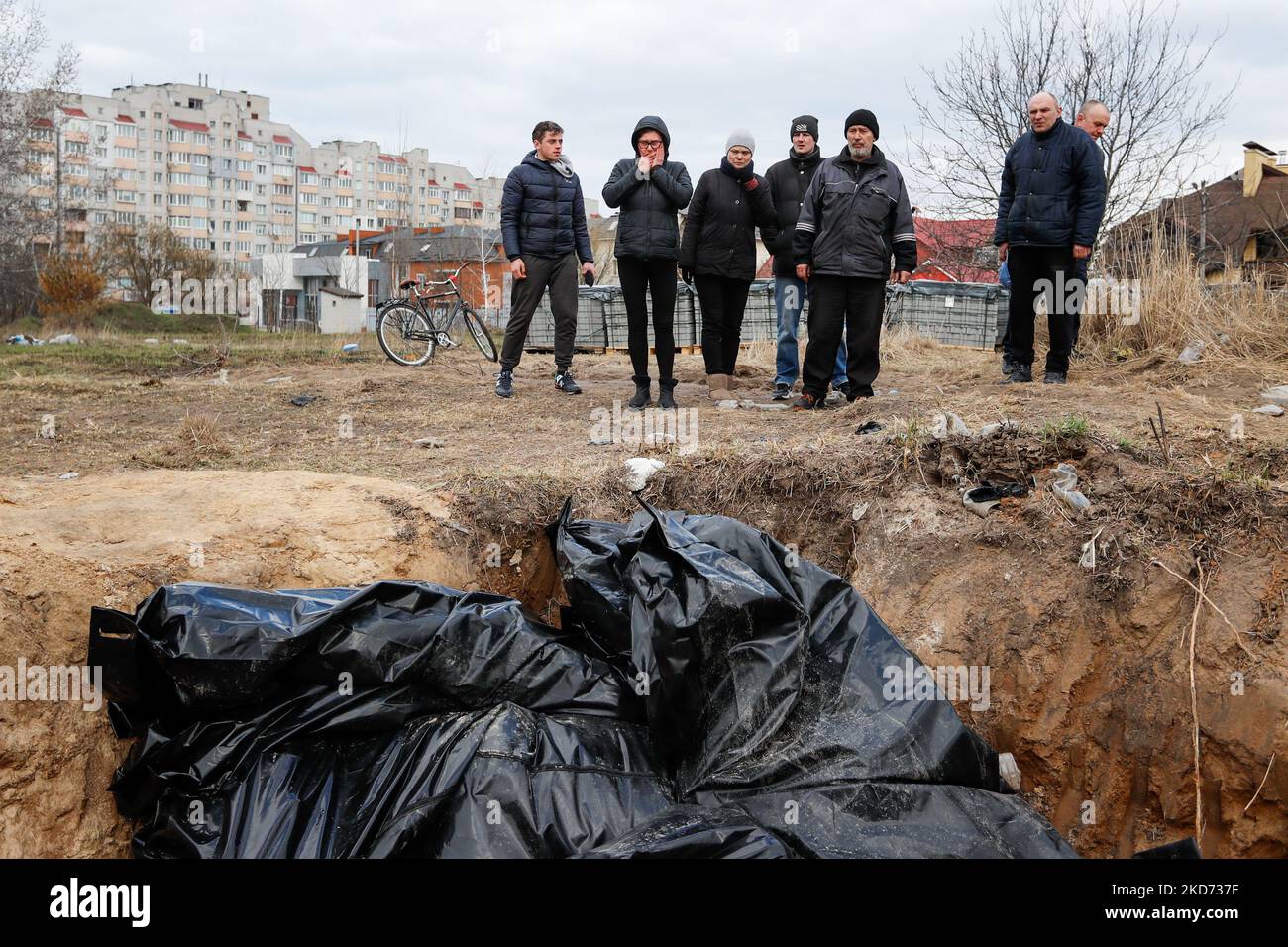 A Ukrainian woman stands in tears in front of a grave behind a church ...