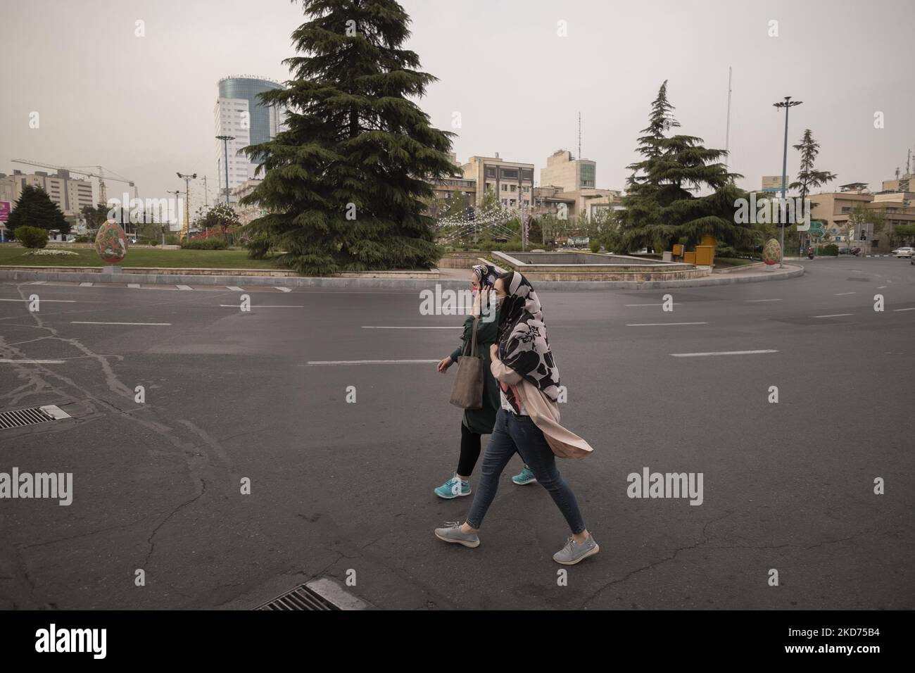 Two Iranian women wearing protective face masks walk along an avenue in ...