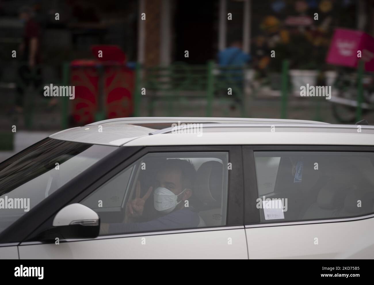 An Iranian driver wearing a protective face mask flashes a Victory sign ...