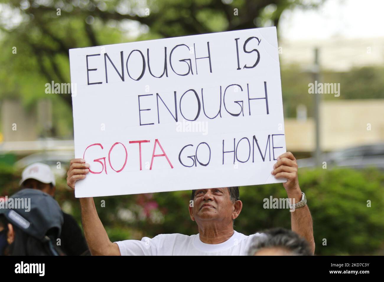 A man holds a sign which reads, "Enough is enough, GOTA go home," a ...