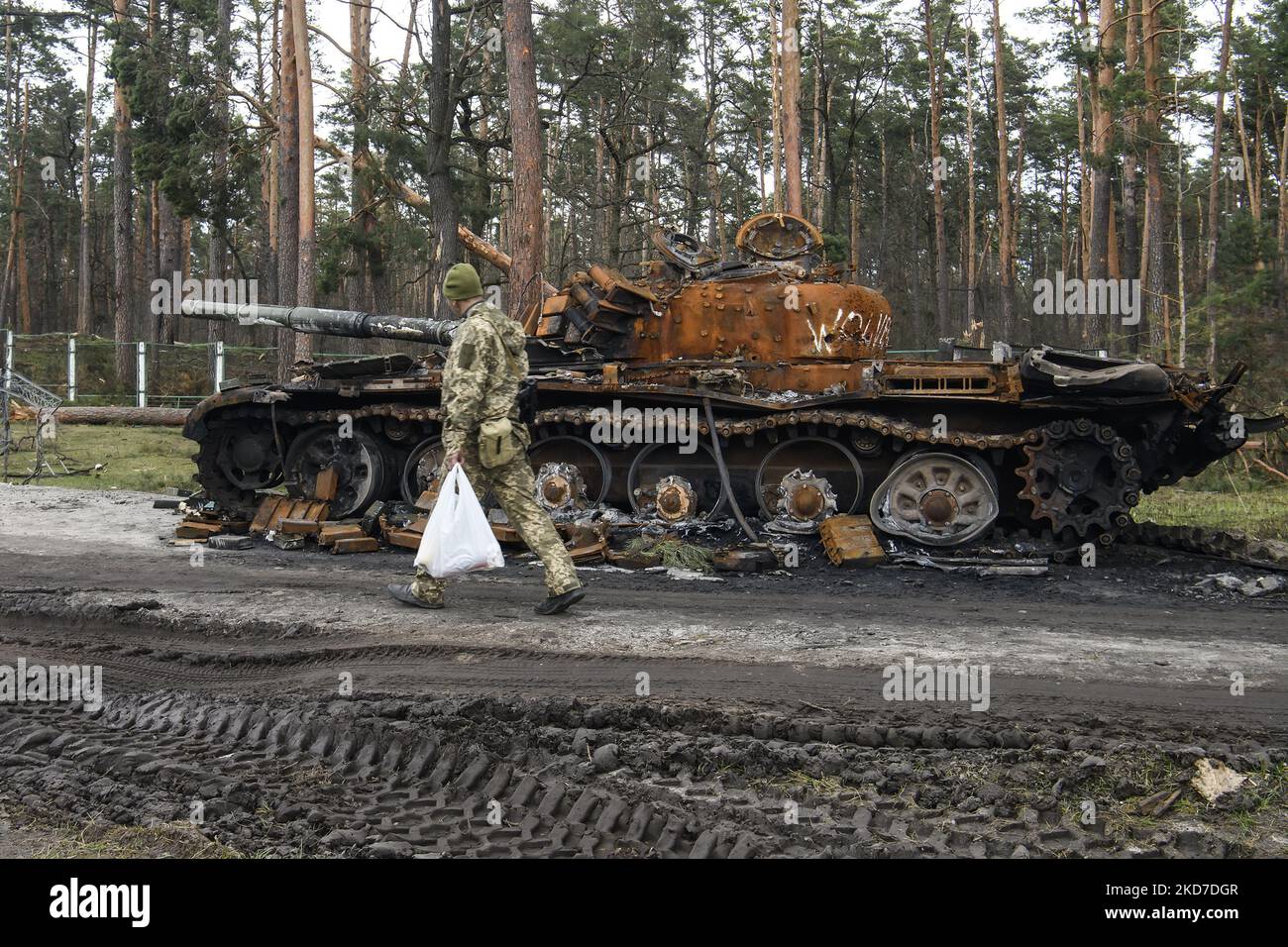 Ukrainian serviceman goes past destroyed Russian military tank near ...