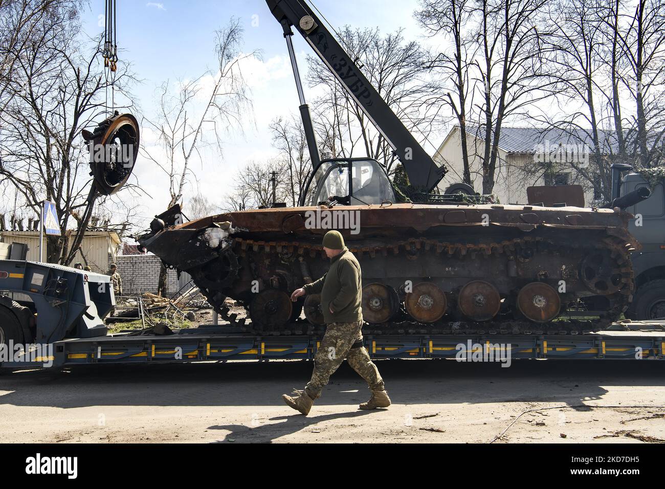 Workers remove destroyed Russian military tank from the road near ...