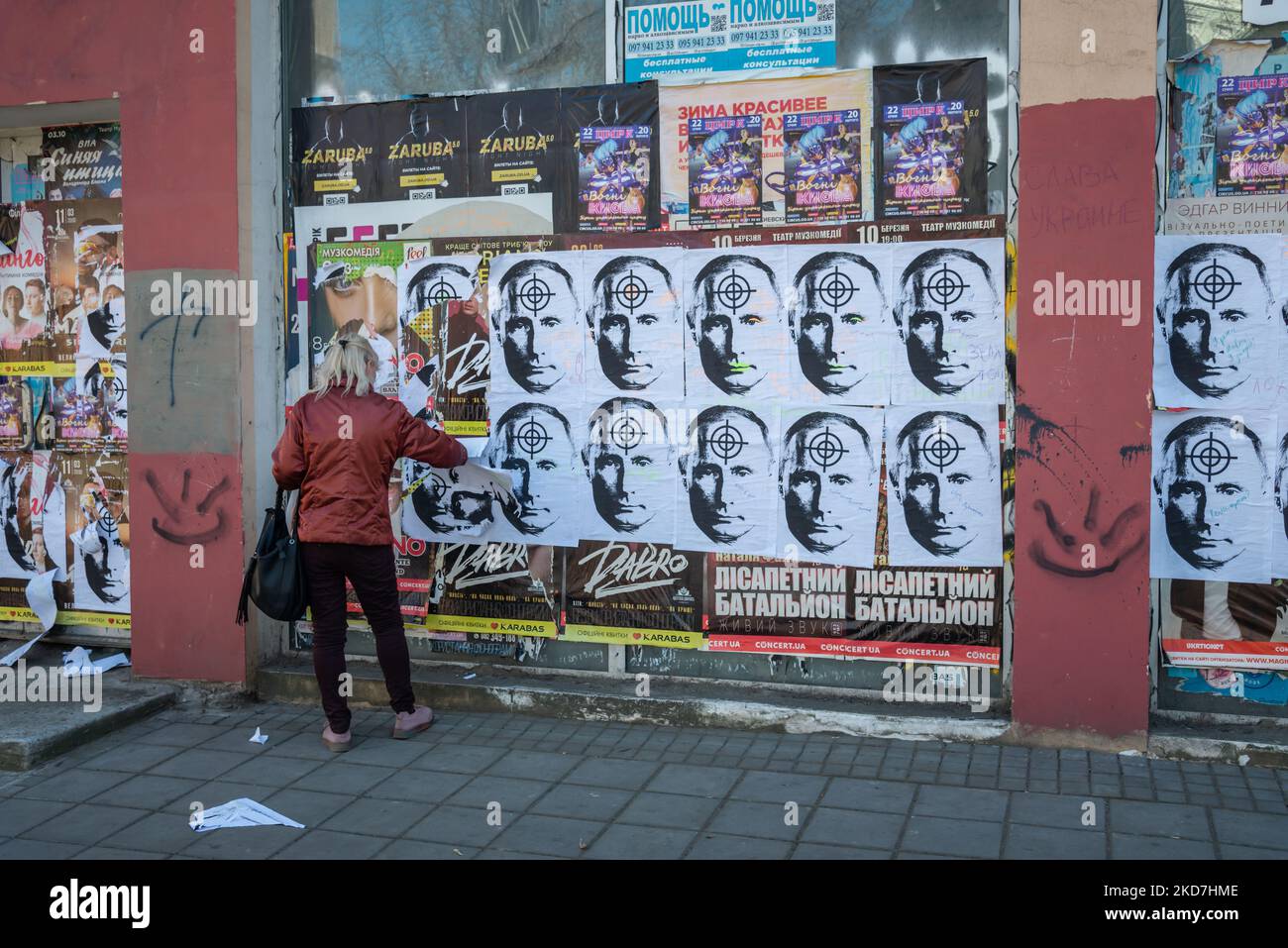 A woman is sees tear away a series of poster depicting the Russian ...