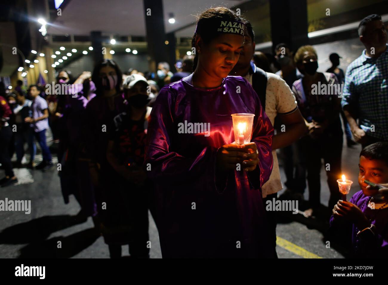 A woman wearing the attire of the Nazareno de San Pablo holds a candle ...