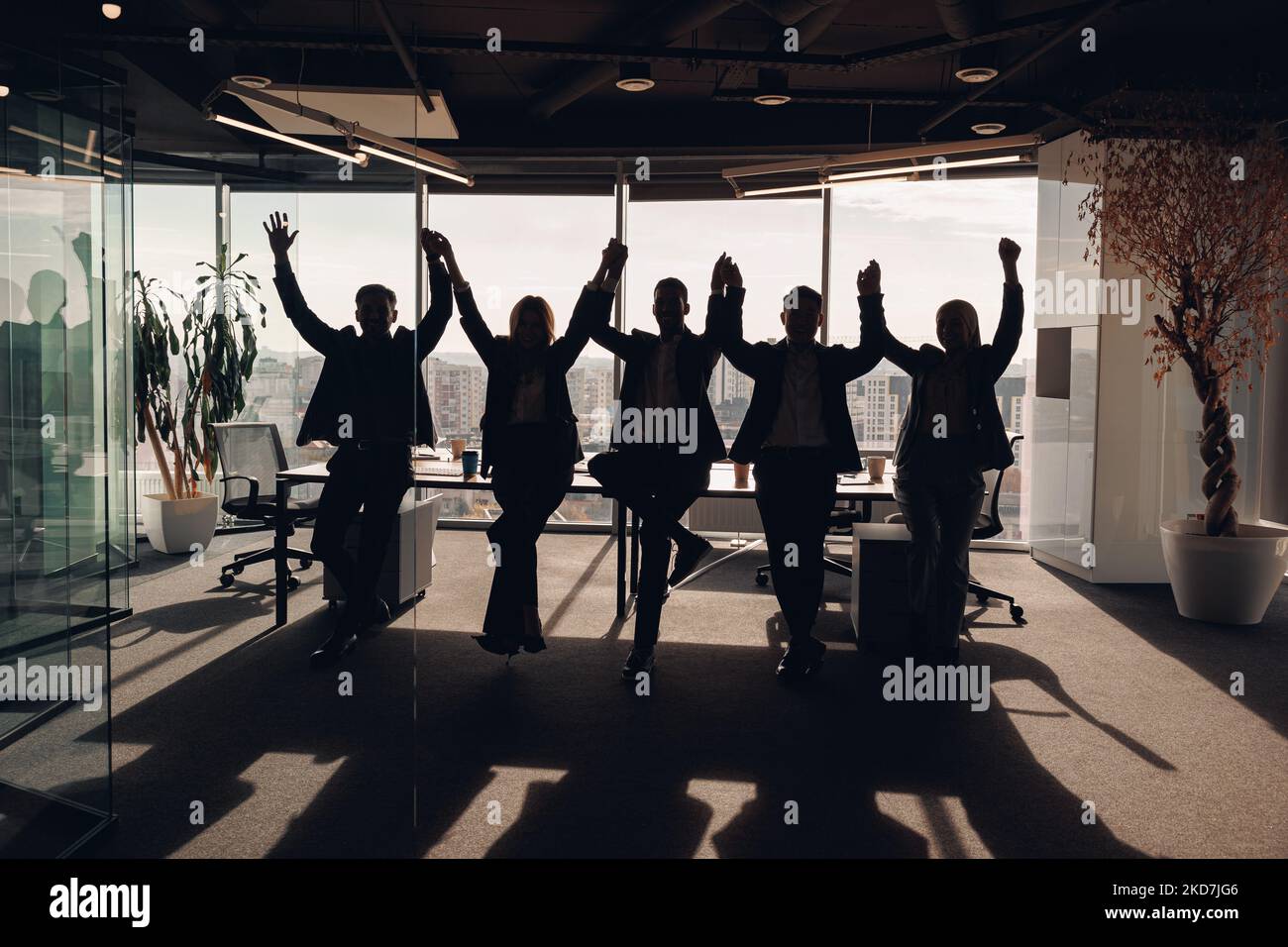 Silhouette photo of business people with raised hands while standing in ...