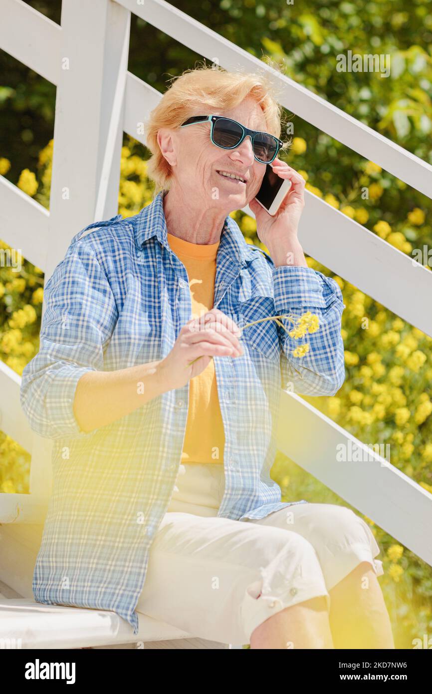 Mature woman sitting alone on the terrace of beach cafe and using ...