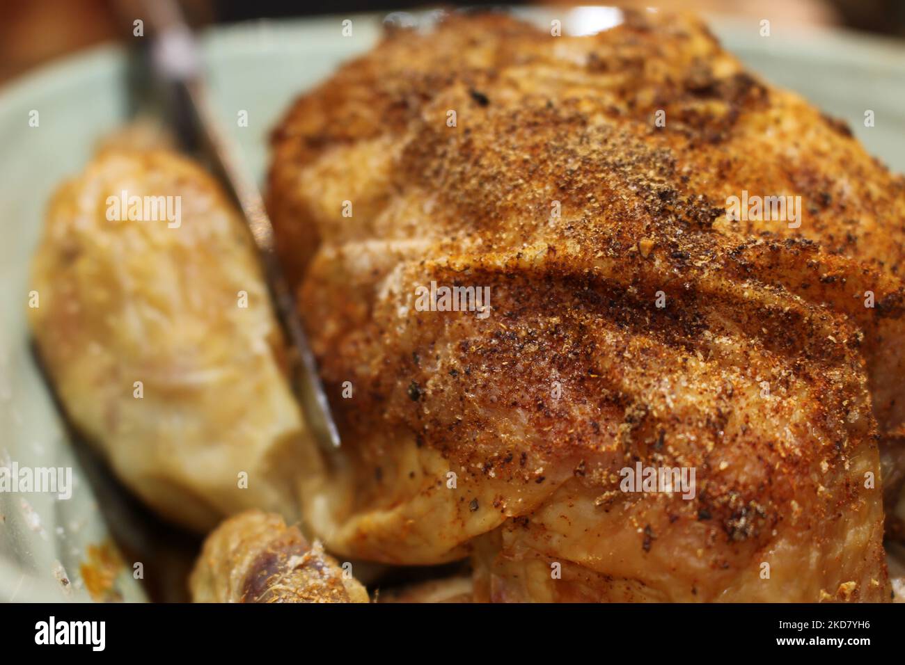 Home made seasoned and cooked whole roast chicken in a tray. Close up ...