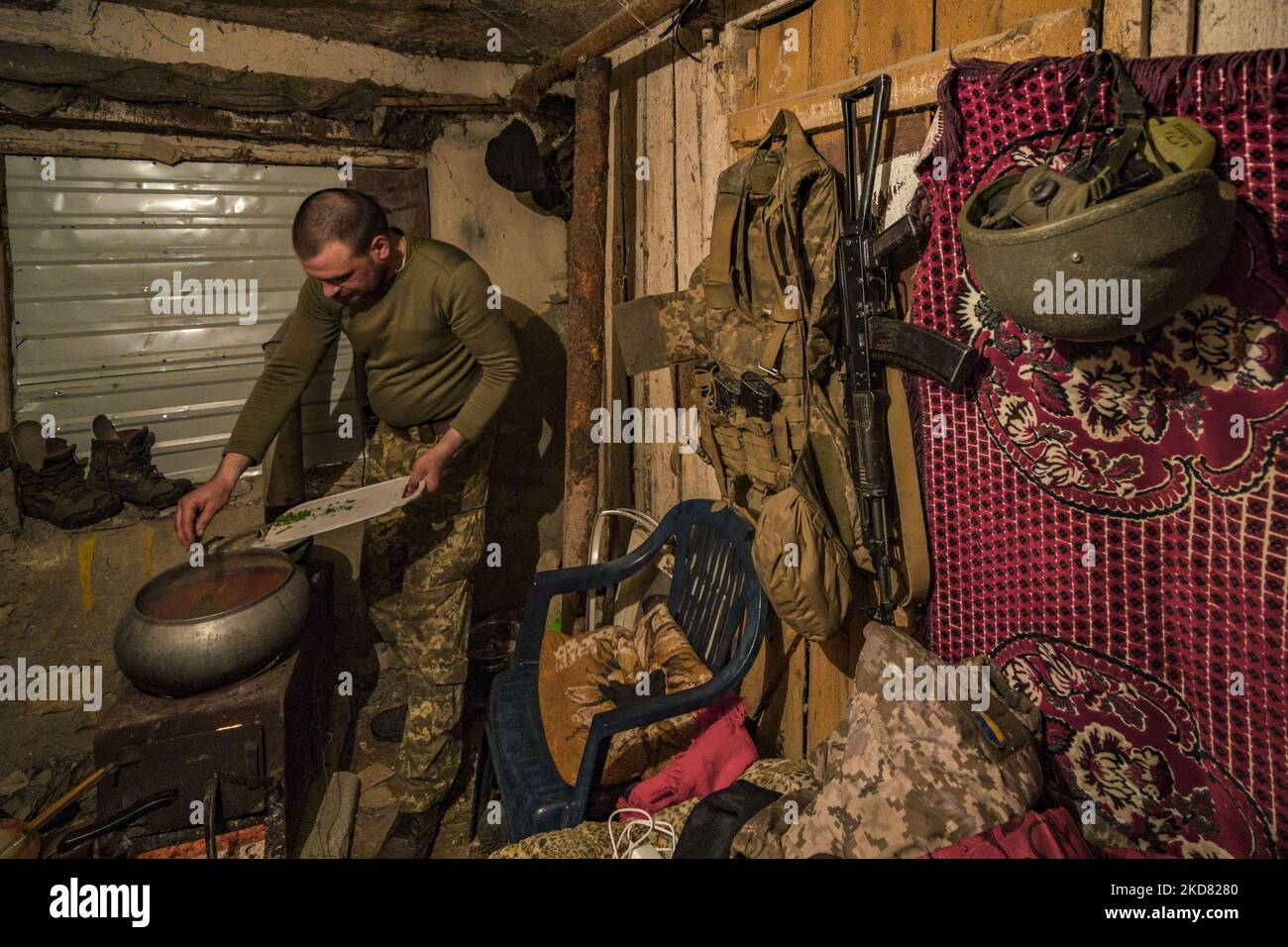 Ukrainian soldier prepares the dinner in a basement shelter near the ...