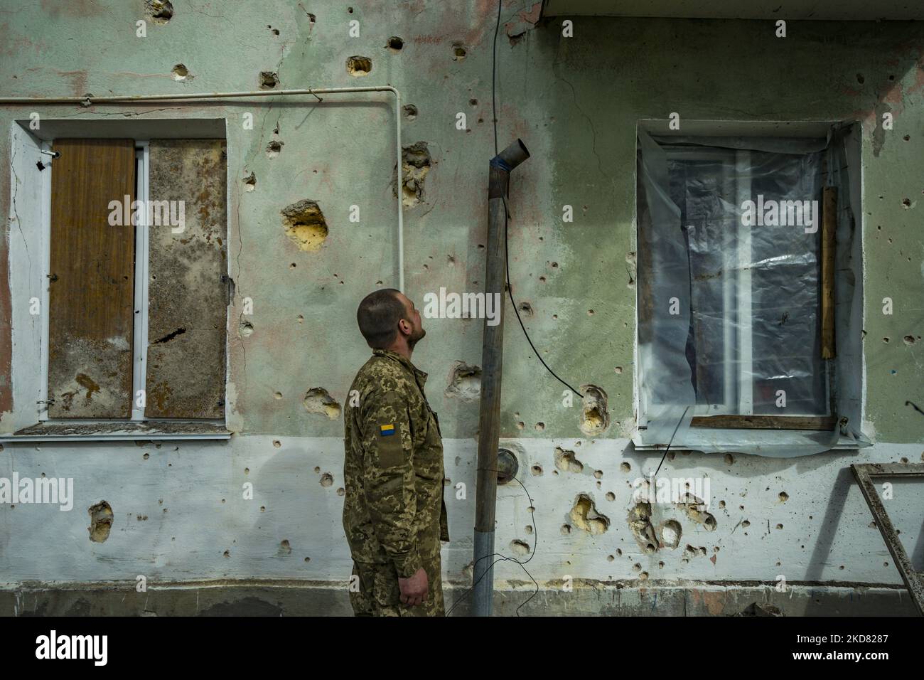 Ukrainian soldier checks the destruction of the shrapnel in a wall of a ...