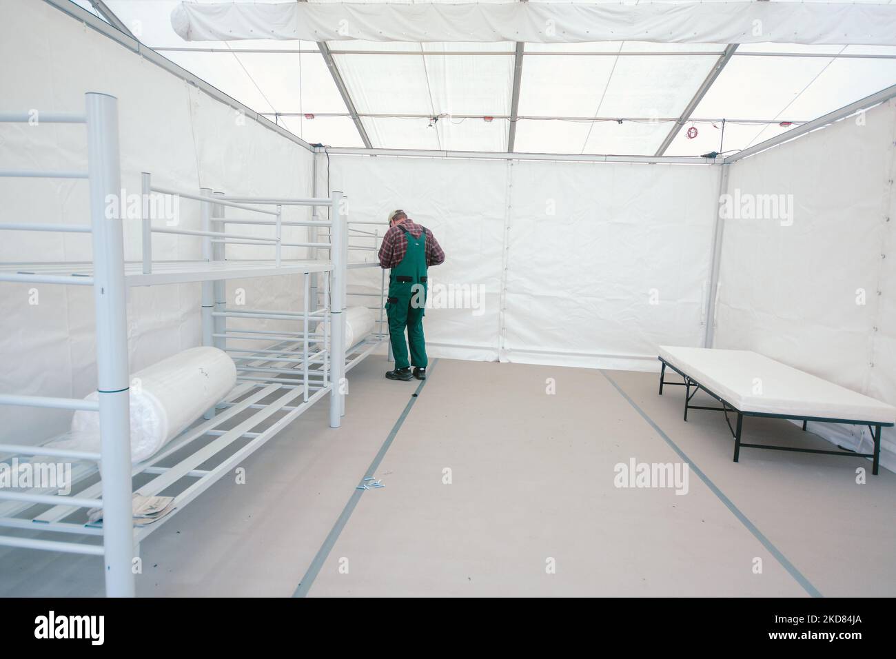a workes is seen assemble a bed during the preview of new refugee camps ...