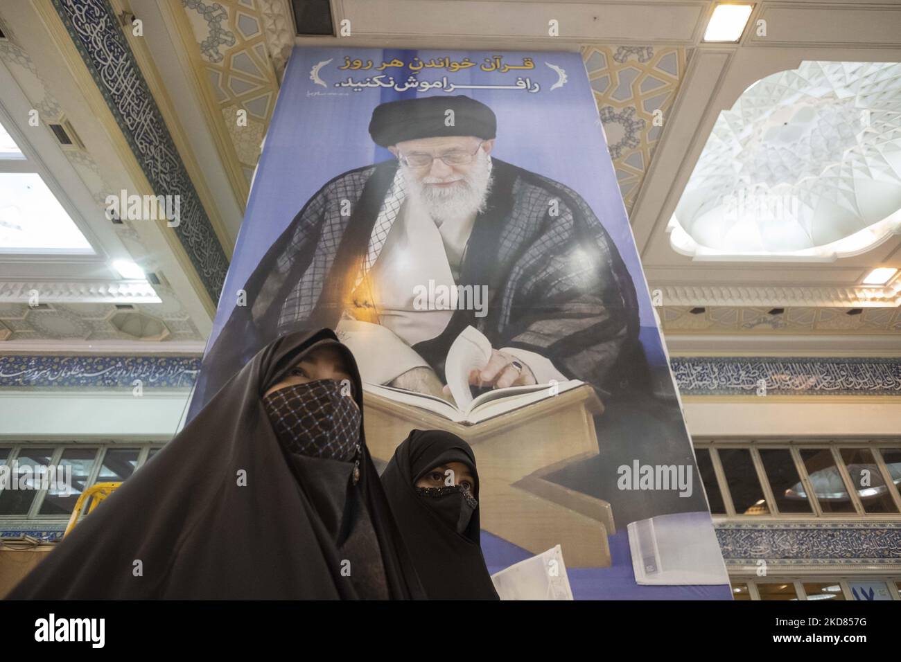 Two Iranian veiled women wearing protective face masks stand under a ...