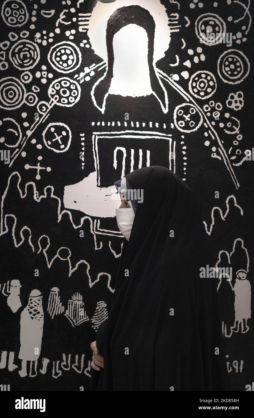 An Iranian veiled woman wearing a protective face mask walks past a ...