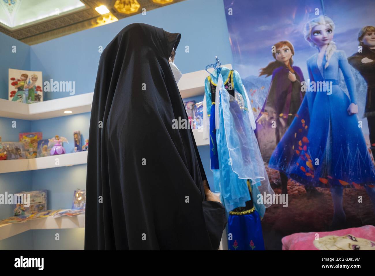 An Iranian young veiled woman wearing a protective face mask observes a ...