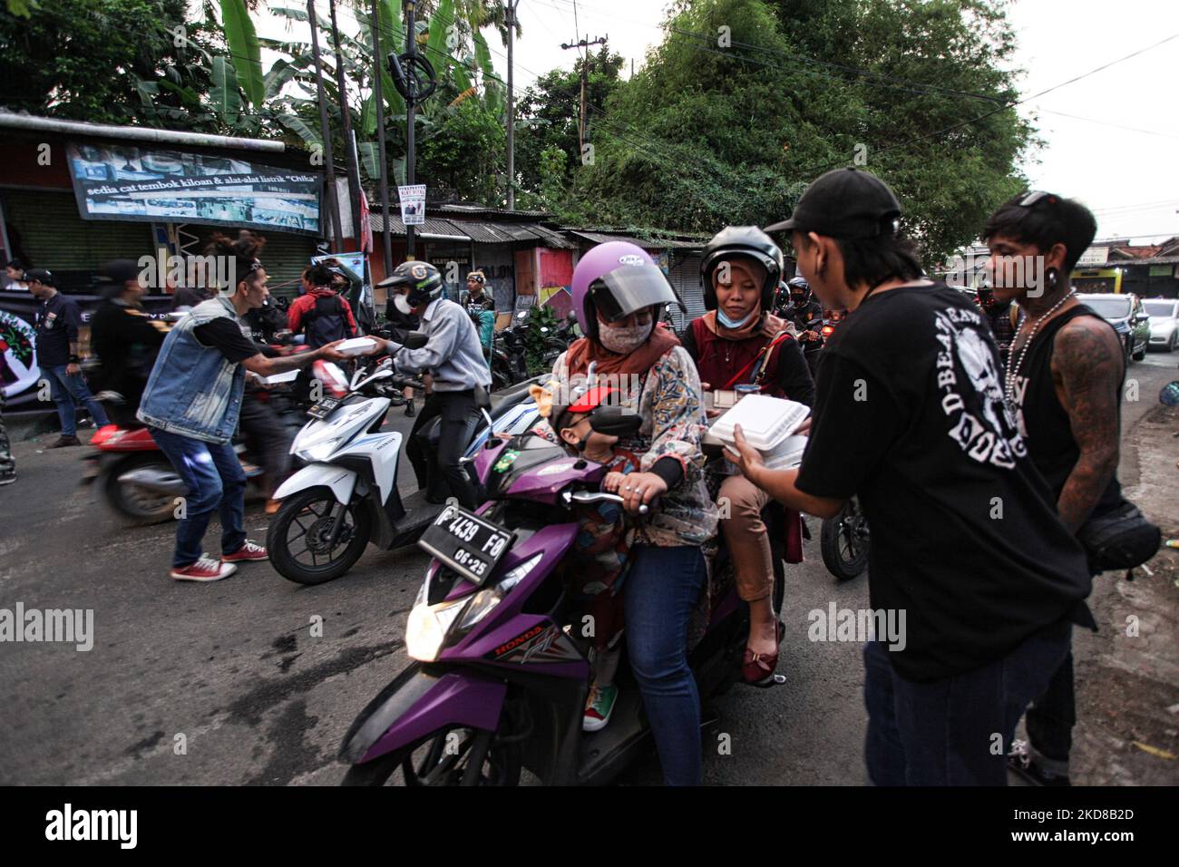An Indonesian street musicians in punk outfits distribute food boxes of ...