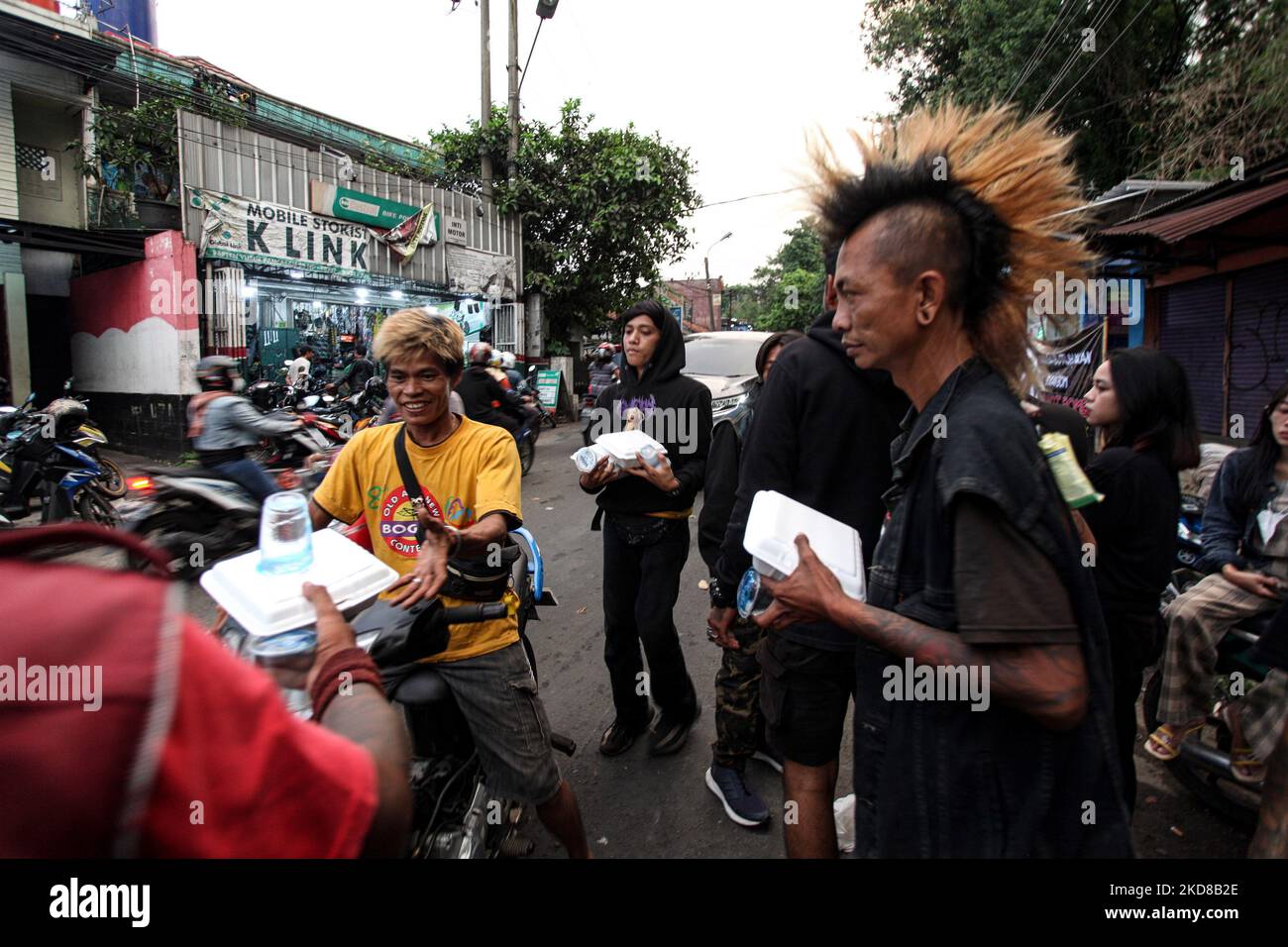 An Indonesian street musicians in punk outfits distribute food boxes of ...
