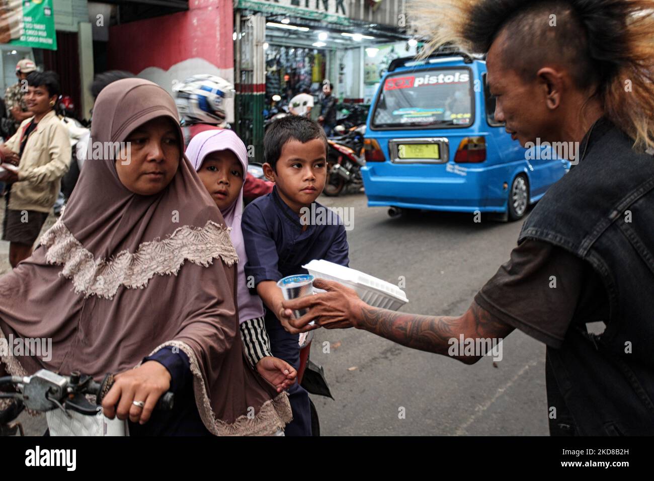 An Indonesian street musicians in punk outfits distribute food boxes of ...