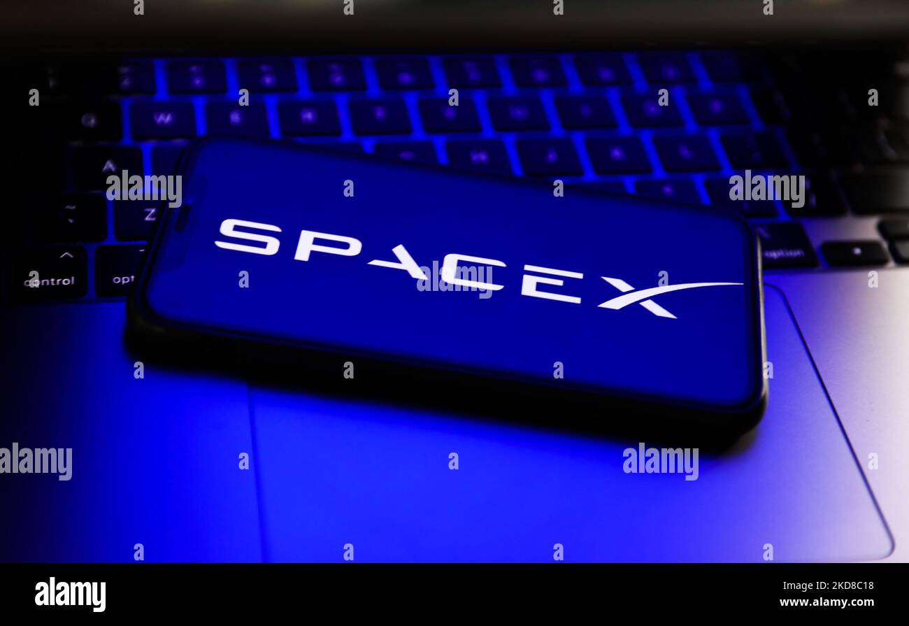 SpaceX logo displayed on a phone screen and a laptop keyboard are seen ...