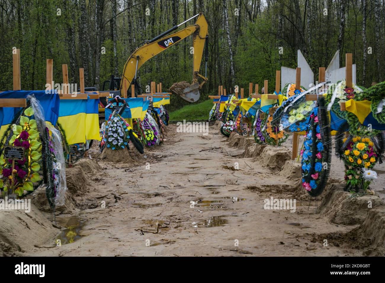 A bulldozer excaves new graves in Yalovshchina cemetery for the ...