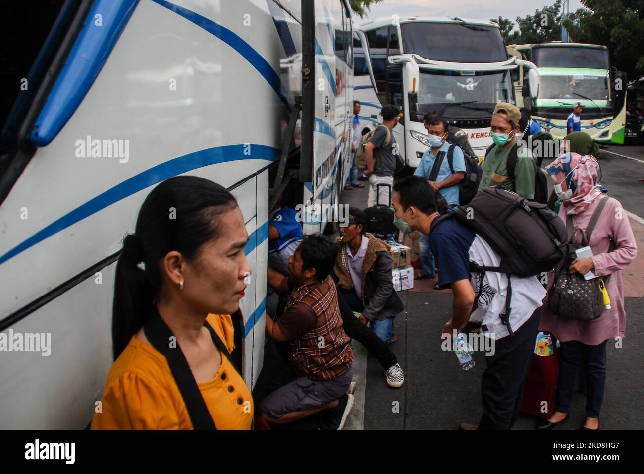 Passengers load their luggage into the trunk of a bus that will take ...