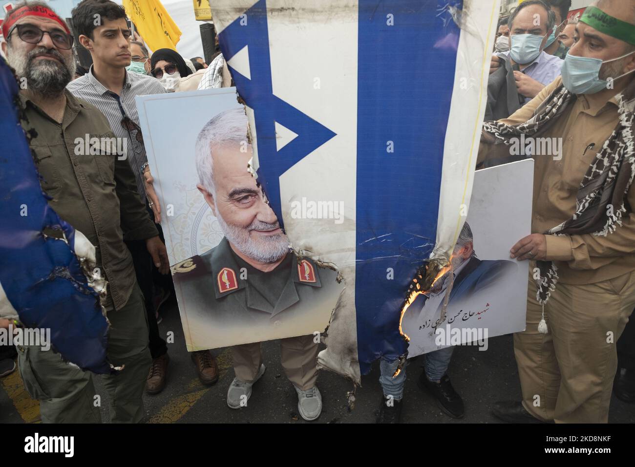 An Iranian demonstrator holds a portrait of the former commander of ...