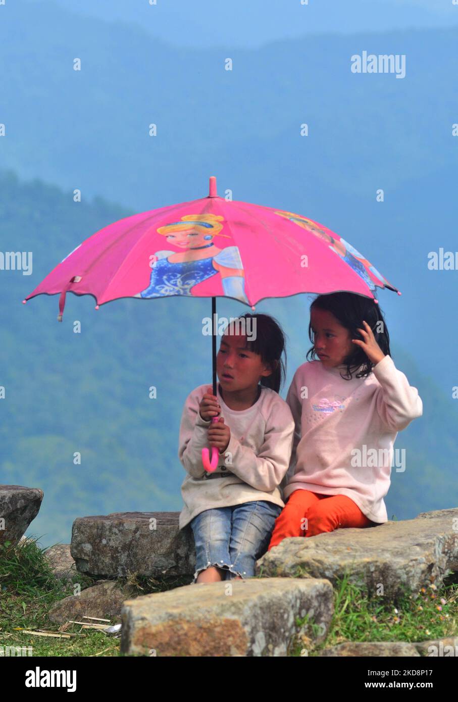 Two Naga kids share an umbrella at a village stone-sitting-out place at ...
