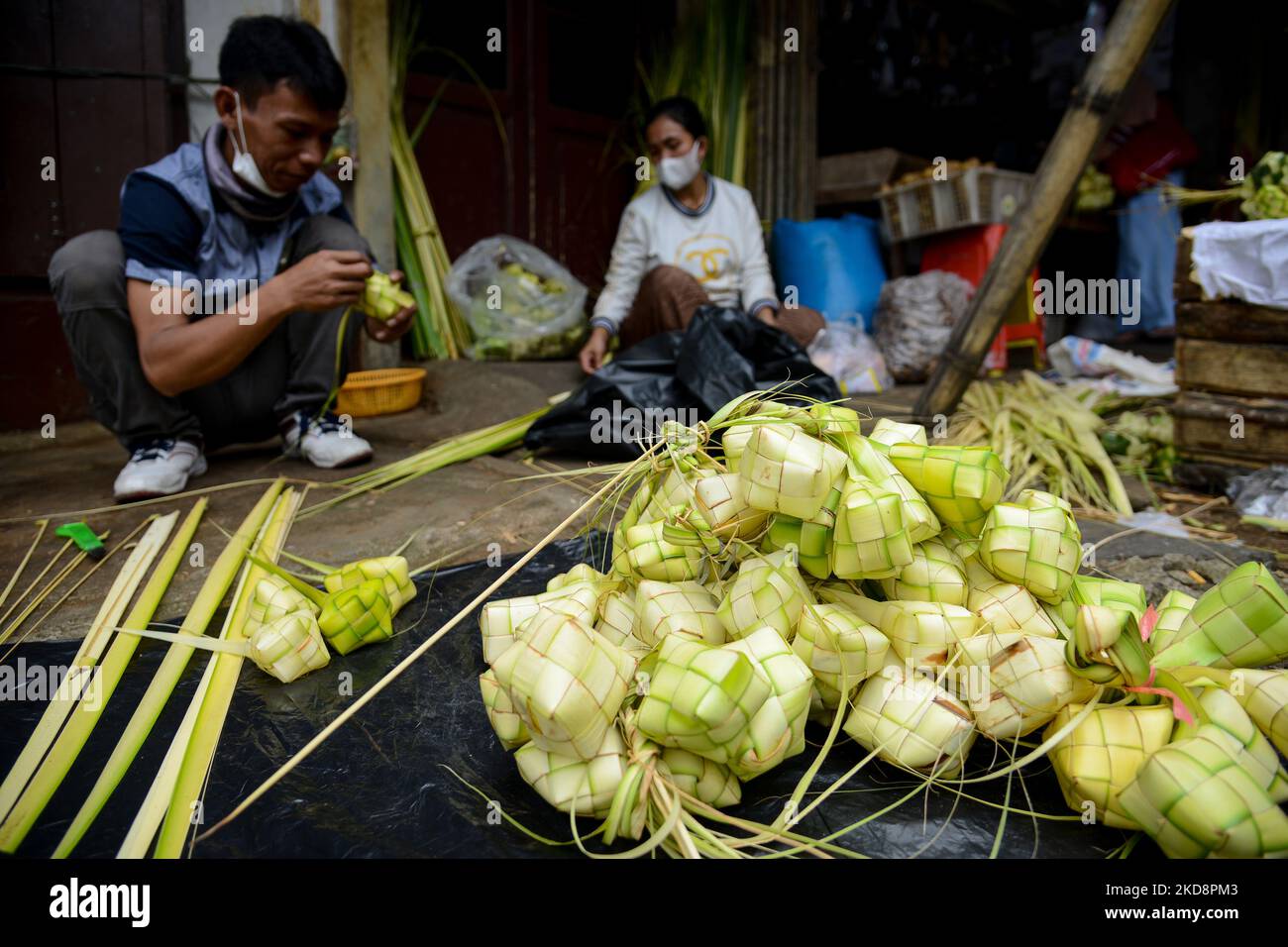 Indonesian street vendors weave palm leaves used to make traditional ...