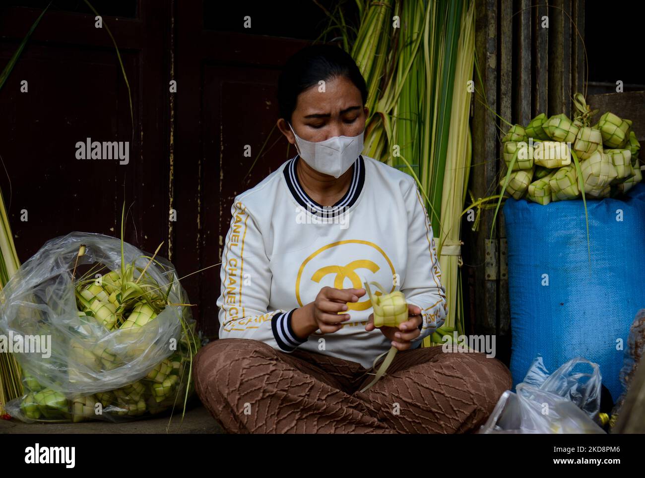 A street vendors weave palm leaves used to make traditional rice cakes ...