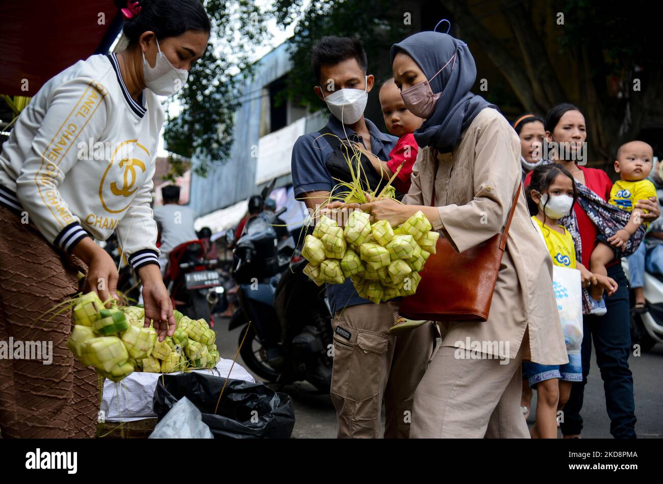 A woman purchases ketupat, a shell made from a palm leaves used to make ...