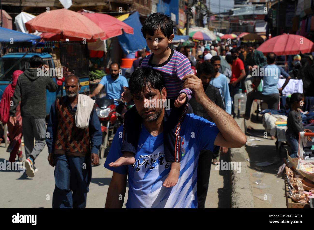 A Man carries a kid on his shoulders as people purchase goods ahead of ...