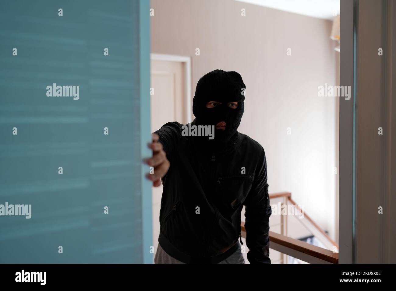 A man wearing a balaclava on his face running in a room- a concept of ...
