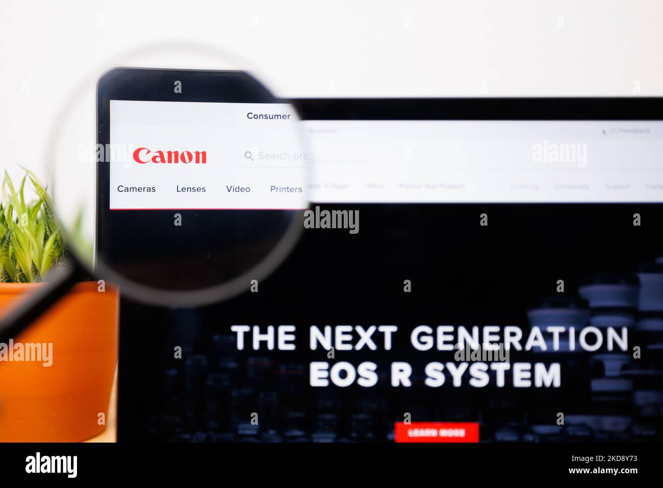 A Canon Logo under a magnifying glass on Canon Website on a Laptop ...