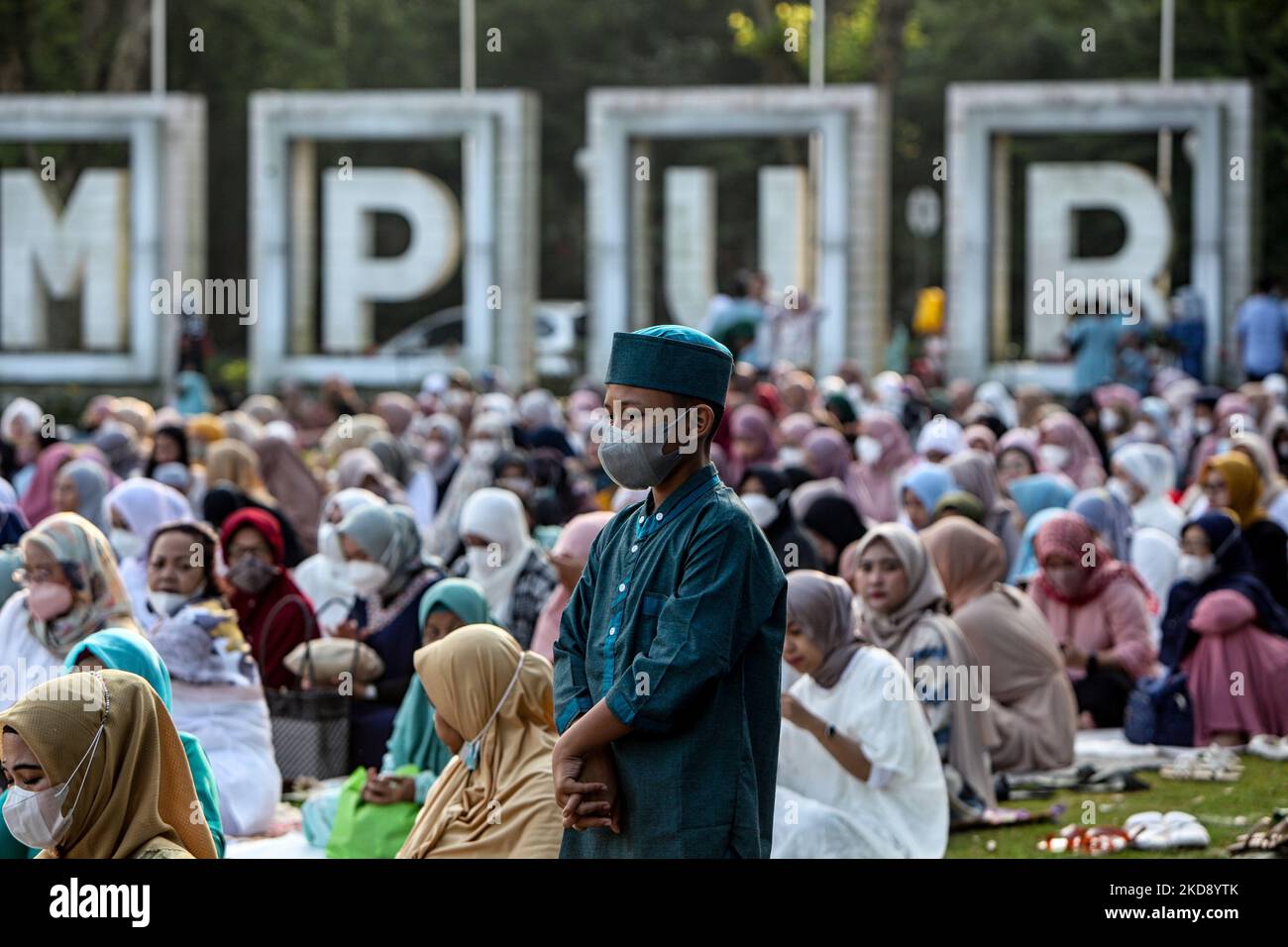 A young boy stands among Indonesian Muslims as they attend Eid al-Fitr ...