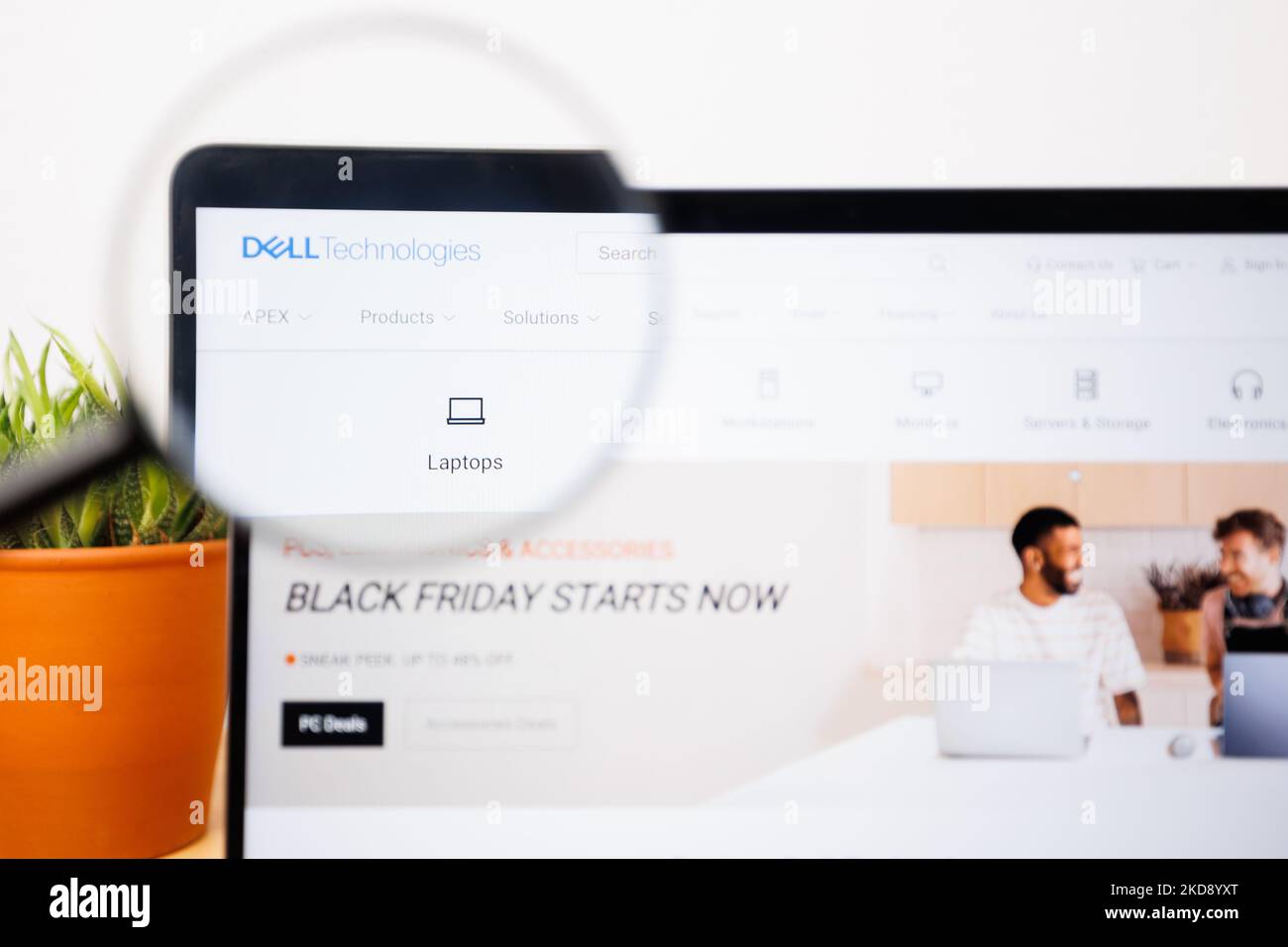 A DELL Logo under a magnifying glass. DELL Website on Laptop screen ...