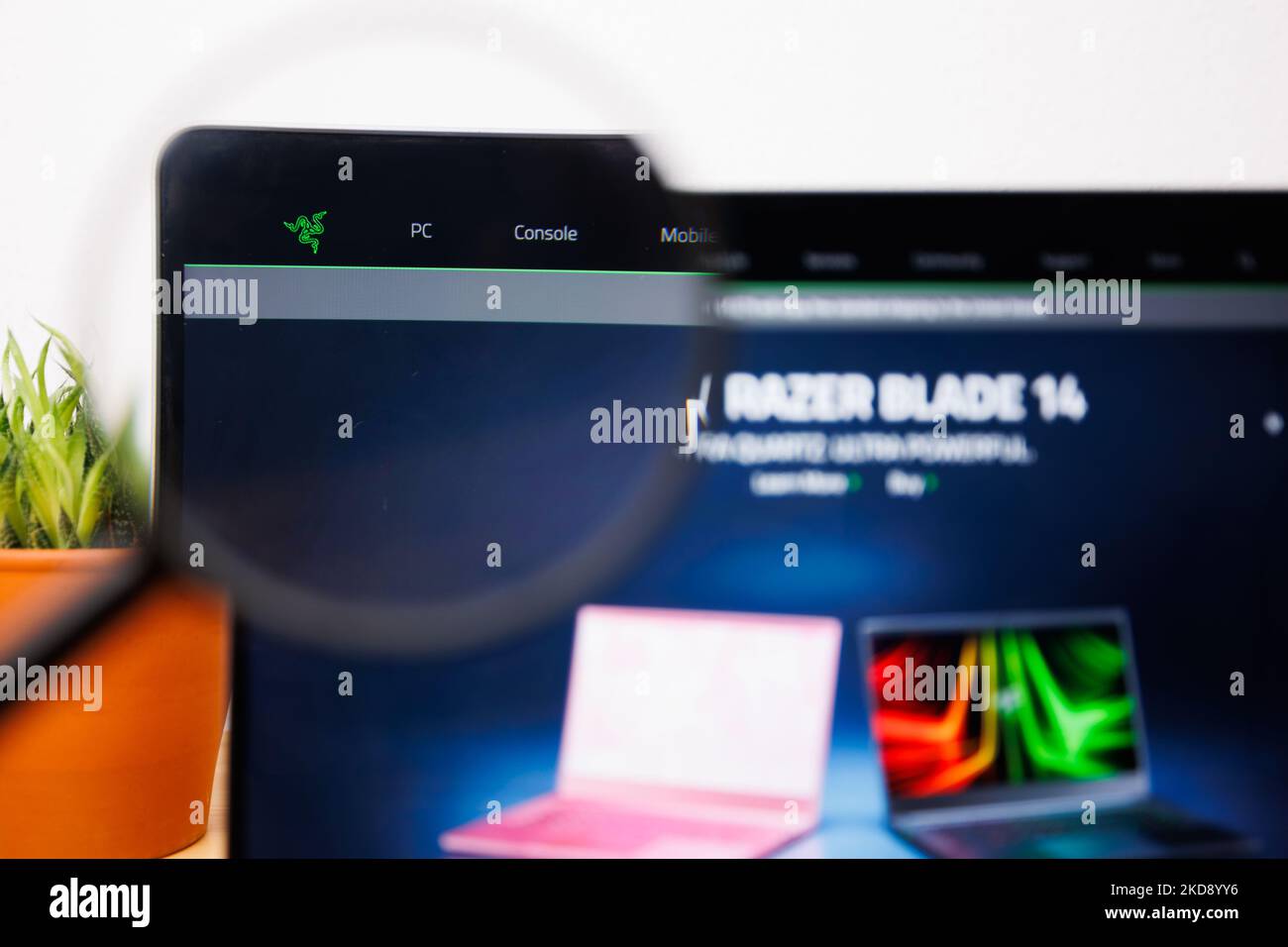 A Razer Logo under a magnifying glass. Razer Website on Laptop screen ...
