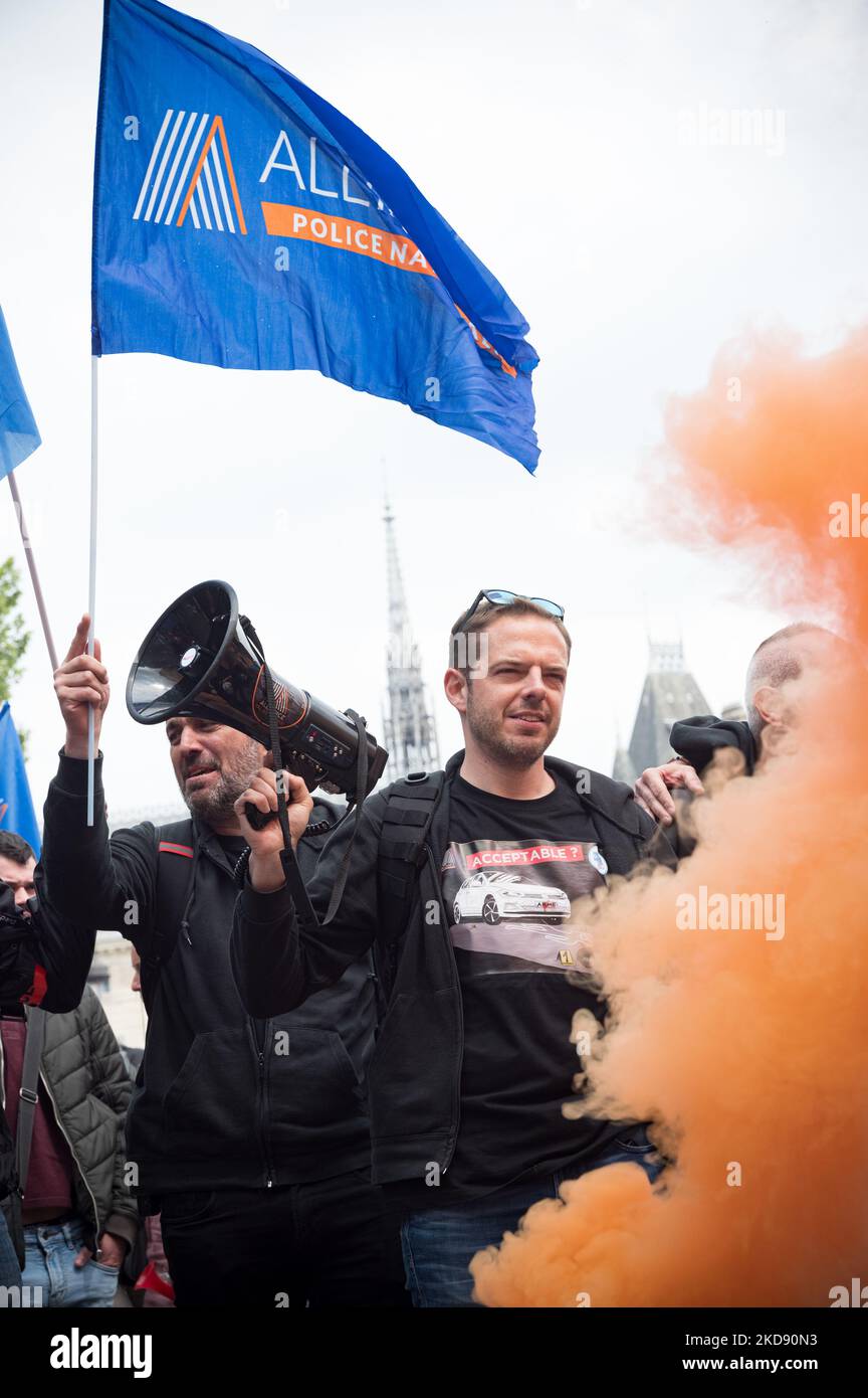 Police officers stand behind a cloud of blue and orange smoke during a ...