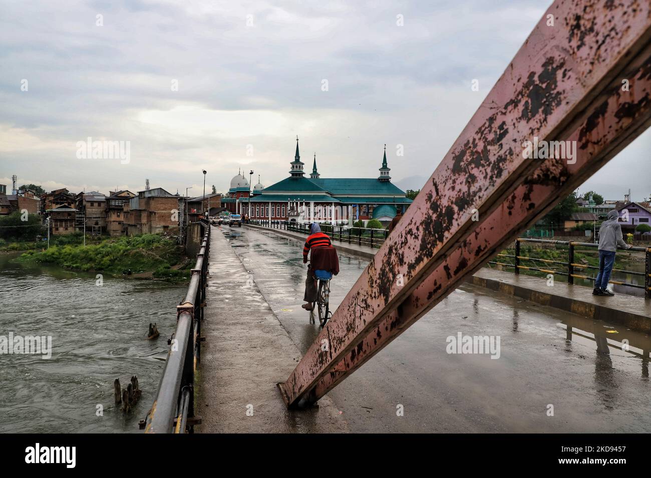 A Cyclist moves over a bridge during light rainfall in Sopore district ...