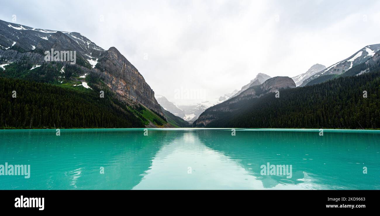 A beautiful shot of a lake with a snowy mountain and gray sky with ...
