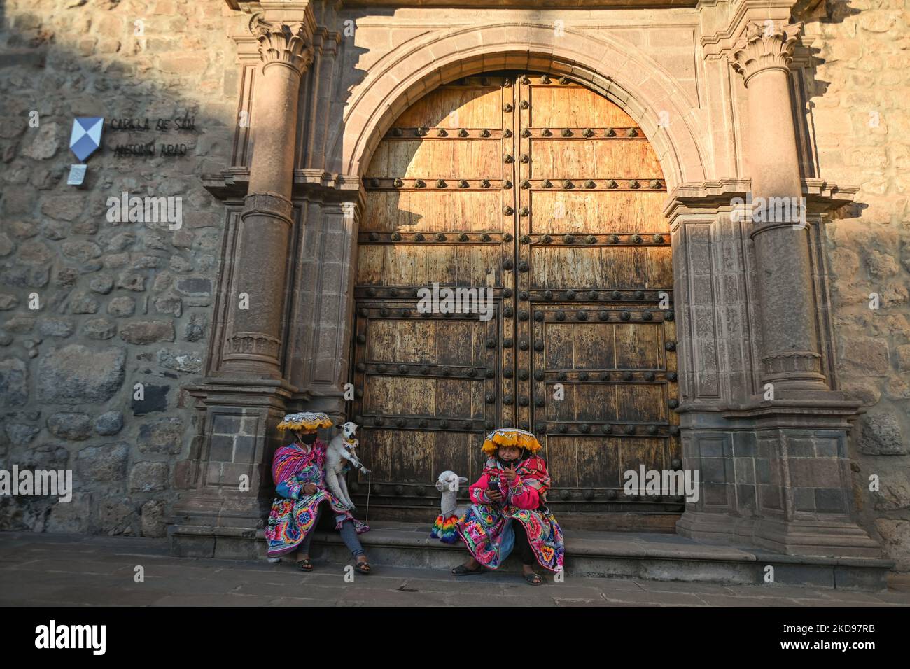 Traditionally dressed Quechua girls with young llama and lamb, seat ...