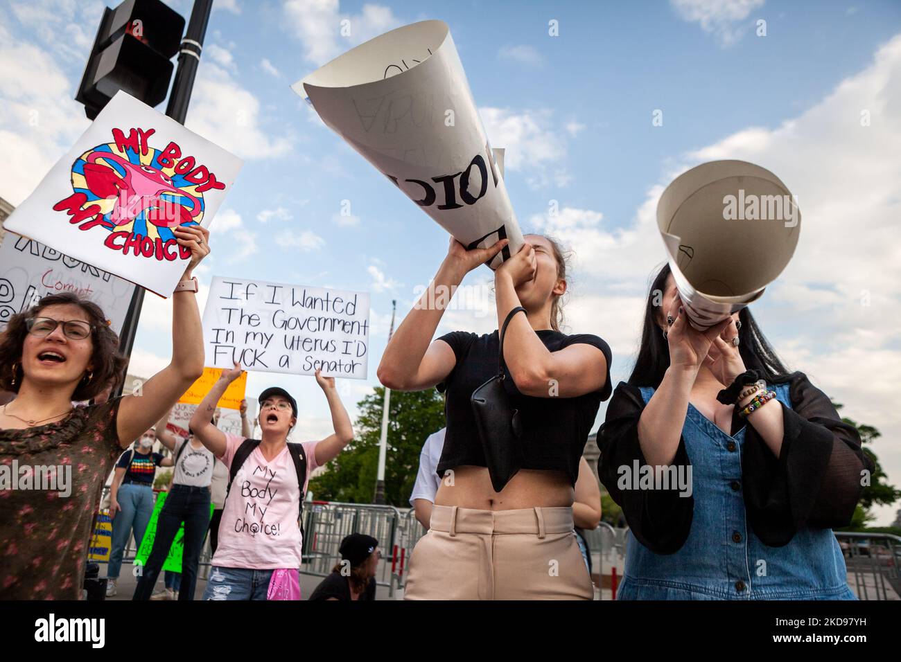 Protesters chant and cheer, some using their signs as megaphones during ...